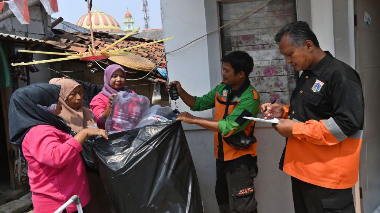 Petugas bank sampah menimbang limbah plastik dari warga di RW 01 Kelurahan Kamal Muara ...